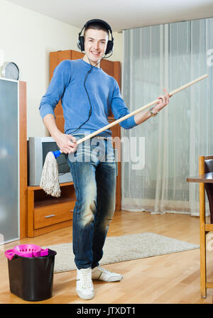 Cheerful man playing with mop in living room Stock Photo - Alamy