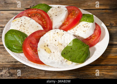 Green plate with traditional Italian Caprese salad and olive oil ...