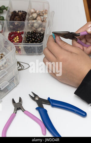Person making jewelry using wire, chains and beads and other materials ...