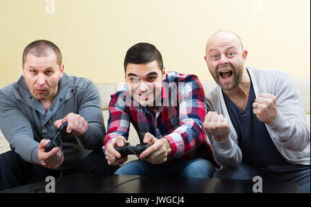 Three shouting friends playing video games at house party Stock Photo ...