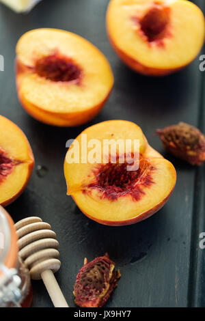 Cutting peaches in half for making grilled peaches Stock Photo - Alamy