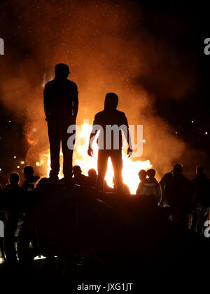 People watch a bonfire, from the top of a cannon on Derry city walls in ...
