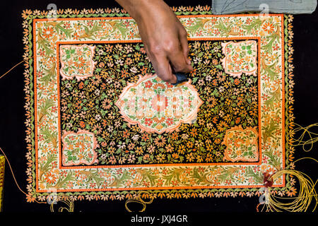 A man creating an embroidered Zardozi wall hanging viewed from above ...