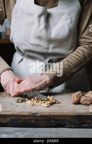 Step by step. Chopping walnuts with kitchen knife on a wood cutting ...