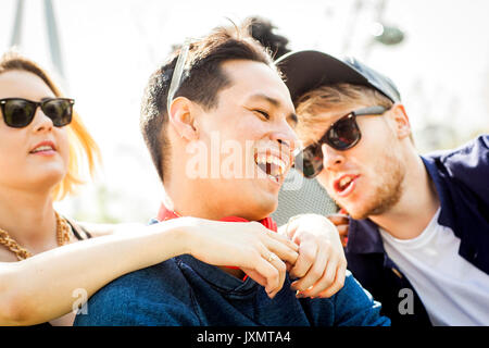 Three friends fooling around outdoors, young men pulling young woman ...