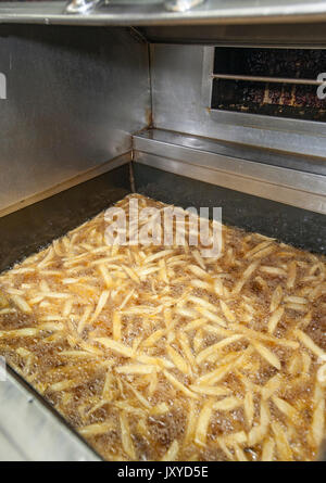 Frying french fries in the fryer in hot oil on the electric stove in ...