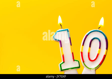 Number 10 birthday celebration candle against a bright yellow ...