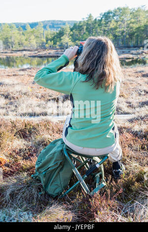 Bird watching. Woman ornithologist with binoculars observes water birds ...