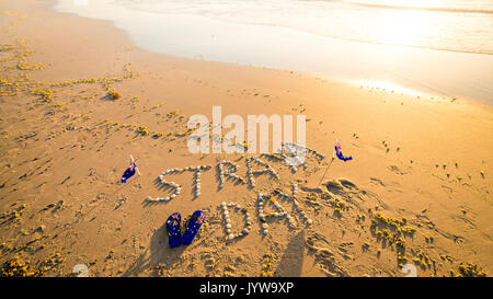Straya text drawn using shells on sand with flags and thongs. Straya is ...