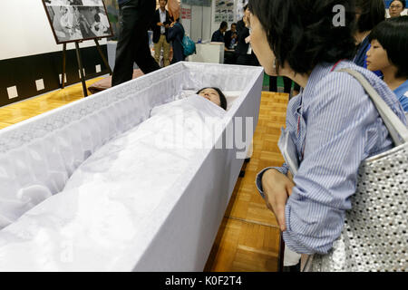 Visitors look at a member of staff inside a coffin after concluding a ...