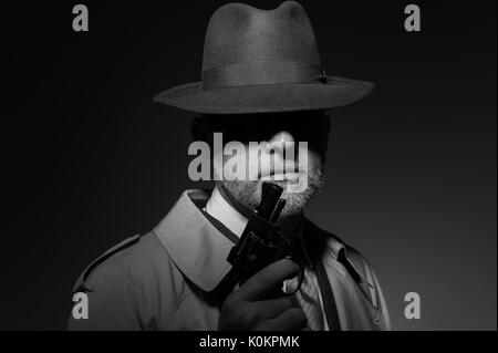 Detective holding a gun, he is wearing a fedora hat and a trench coat ...