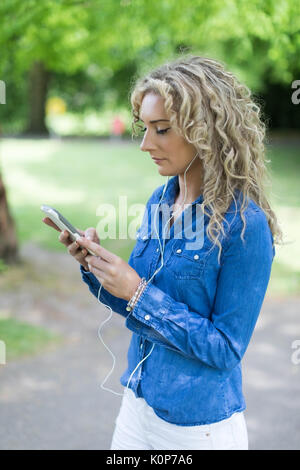 Young adult woman using smartphone and laptop for remote work outdoors ...