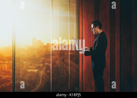 Businessman using laptop with generic office background , night scene ...