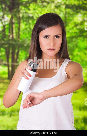 Beautiful young woman using a spay over the insect to kill it, in a ...
