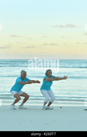 senior couple doing exercises on sandy beach in evening Stock Photo - Alamy