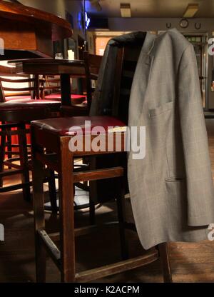 Suit jacket hanging on the back of a bar chair (as if left behind Stock ...