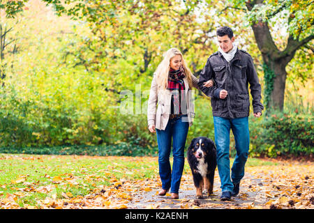 Woman and man having walk with dog in autumn rain Stock Photo - Alamy