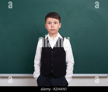 indifferent school boy portrait near green blank chalkboard background ...