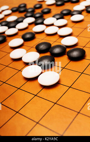black and white stones on a ‘GO’ board made from wood on white ...