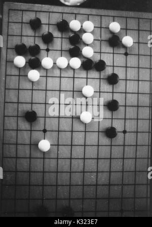 black and white stones on a ‘GO’ board made from wood on white ...