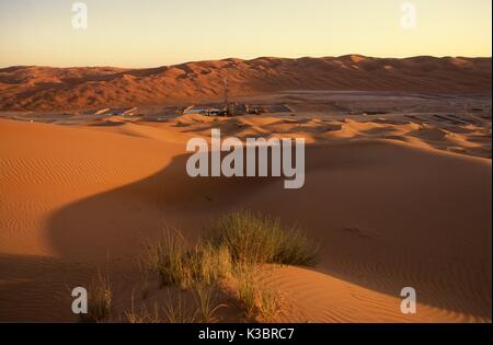 An oil rig searching for oil amongst the sand dunes that will feed into ...