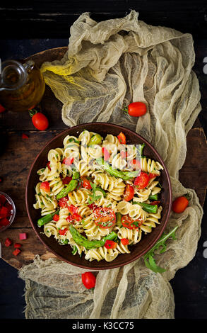 Tasty green pasta with pepper, and tomatoes on wooden table background ...