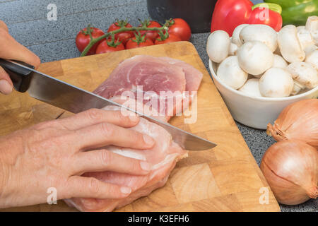 Side view of woman slicing meat on a wooden board Stock Photo - Alamy