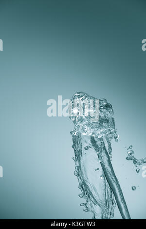 A stream of filtered natural water on a blue background. Splash of ...