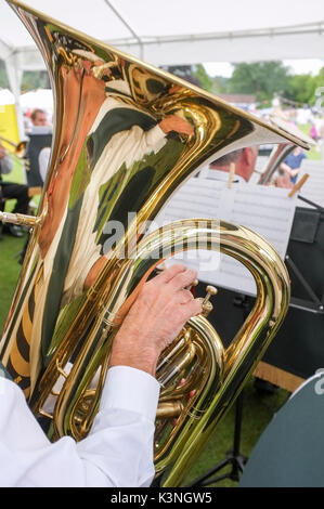 tuba player at brass band with musical notes on stand during open air ...