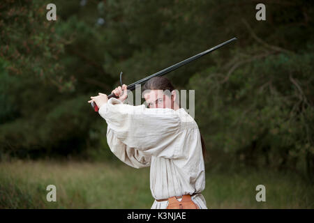 Medieval swordsman in wood clearing takes attacking stance Stock Photo ...