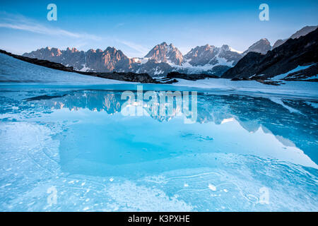 The reflection of the Bernina range in the icy water of little lake ...