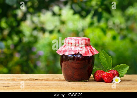 Strawberry jam in a jar on a wooden board. Fermented berries. Copy ...