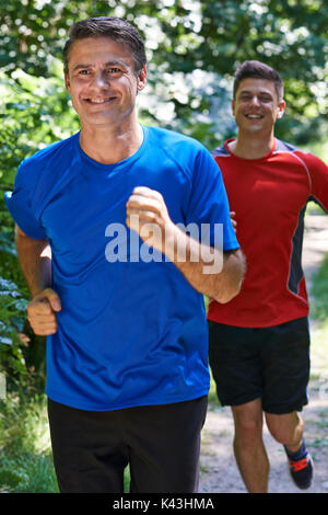 Adult men are jogging together on the beach near ocean Stock Photo - Alamy