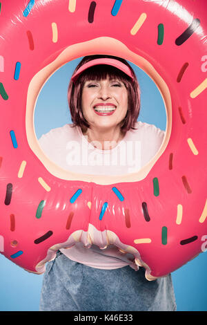 Stylish senior woman in casual clothes and sunglasses gesturing horns ...