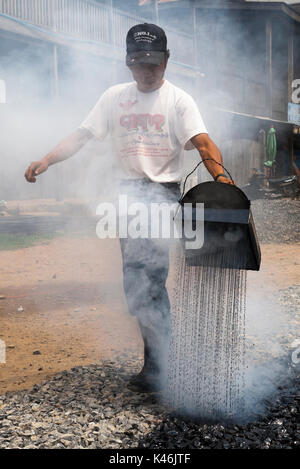 Construction worker repairing road, pouring boiling bitumen by hand ...