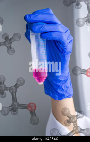 Female researcher is looking at a cell pellet in a tube. Laboratory ...