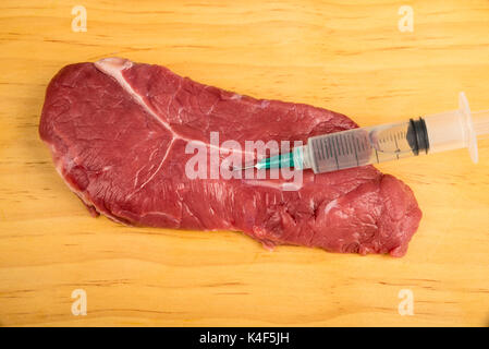 Hormones being injected in a beef steak, a conceptual food manipulation ...