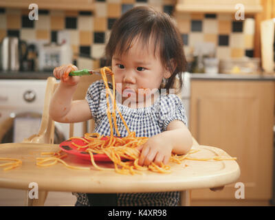 baby girl eating messy spaghetti at home Stock Photo - Alamy
