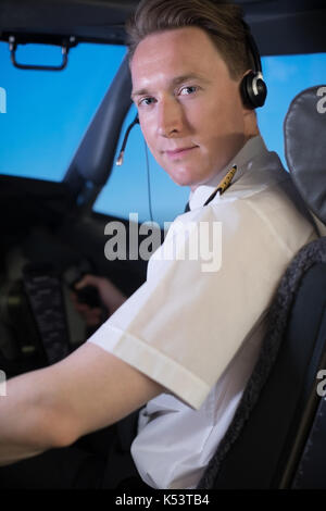 Side view of professional male aviator in oxygen mask turning switch on ...