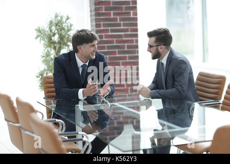 Two businessmen discussing tasks sitting at office table Stock Photo ...
