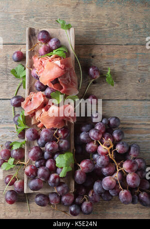 Jamon serrano with parsley and grape on a old wooden table . Healthy ...