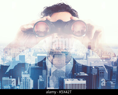 Businessman looking forward to a city with binoculars from skyscraper ...