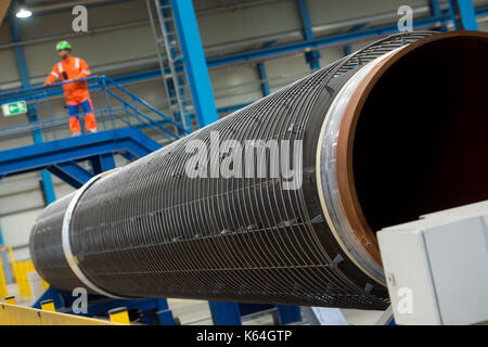 A steel pipe is being coated in concrete in the Wasco coating plant on ...