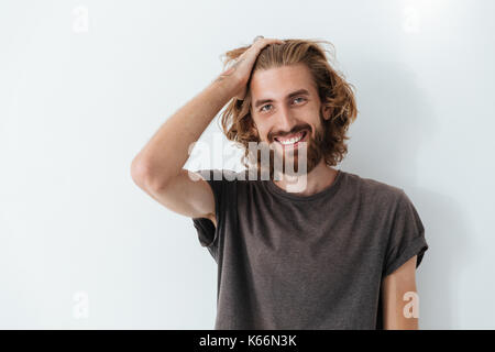 Young caucasian man over grey grunge wall shouting trough megaphone ...
