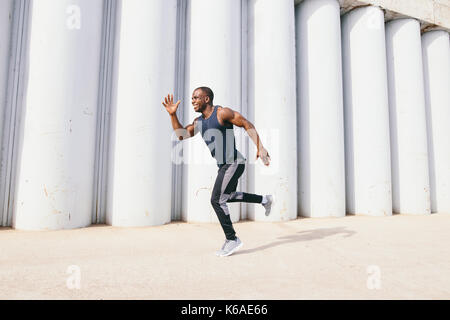 Attractive fit man running fast along countryside road at sunset light ...