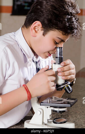 Young boy scientist with microscope examining a sample Stock Photo - Alamy