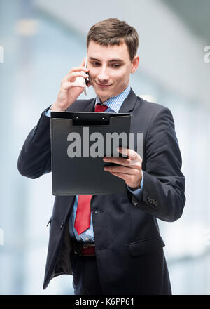 Young man with folder talking by telephone in office Stock Photo - Alamy