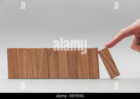 Male hand stopping wooden blocks falling over Stock Photo - Alamy