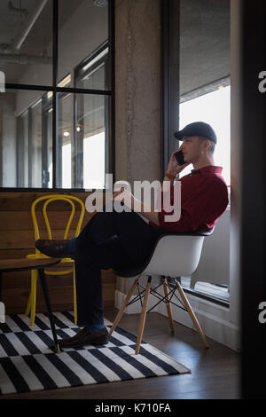 Businessman Talking on Phone While Sitting at Desk With Laptop and ...