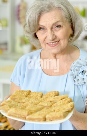 Mature woman holding plate with cookies on white background Stock Photo ...